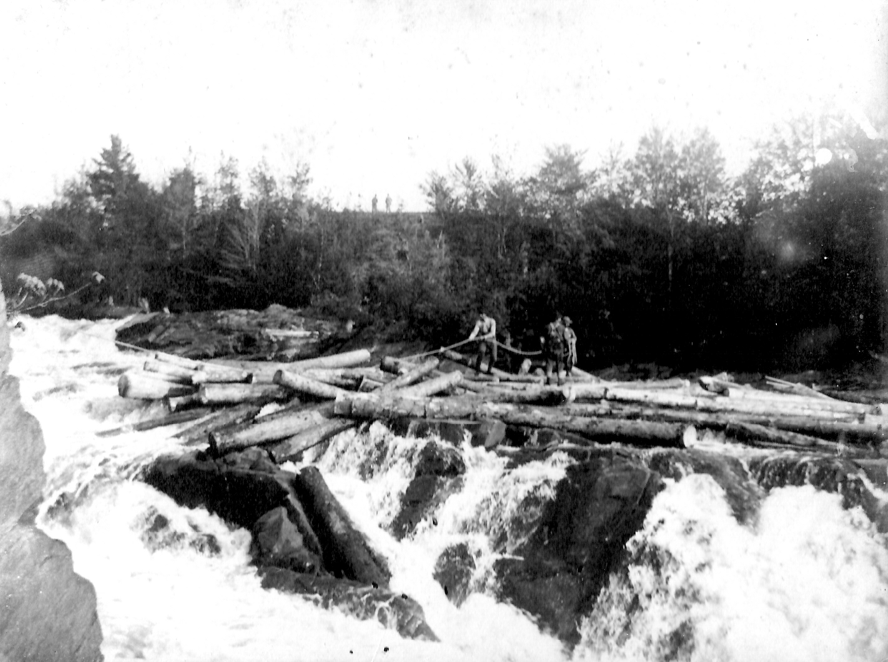 Loggers during a spring log drive on the Racquette River in Colton