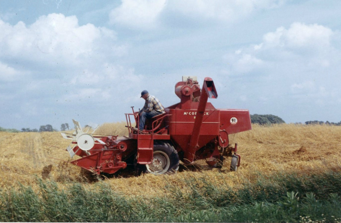 Farmer operating a small combine to harvest oats near Watertown