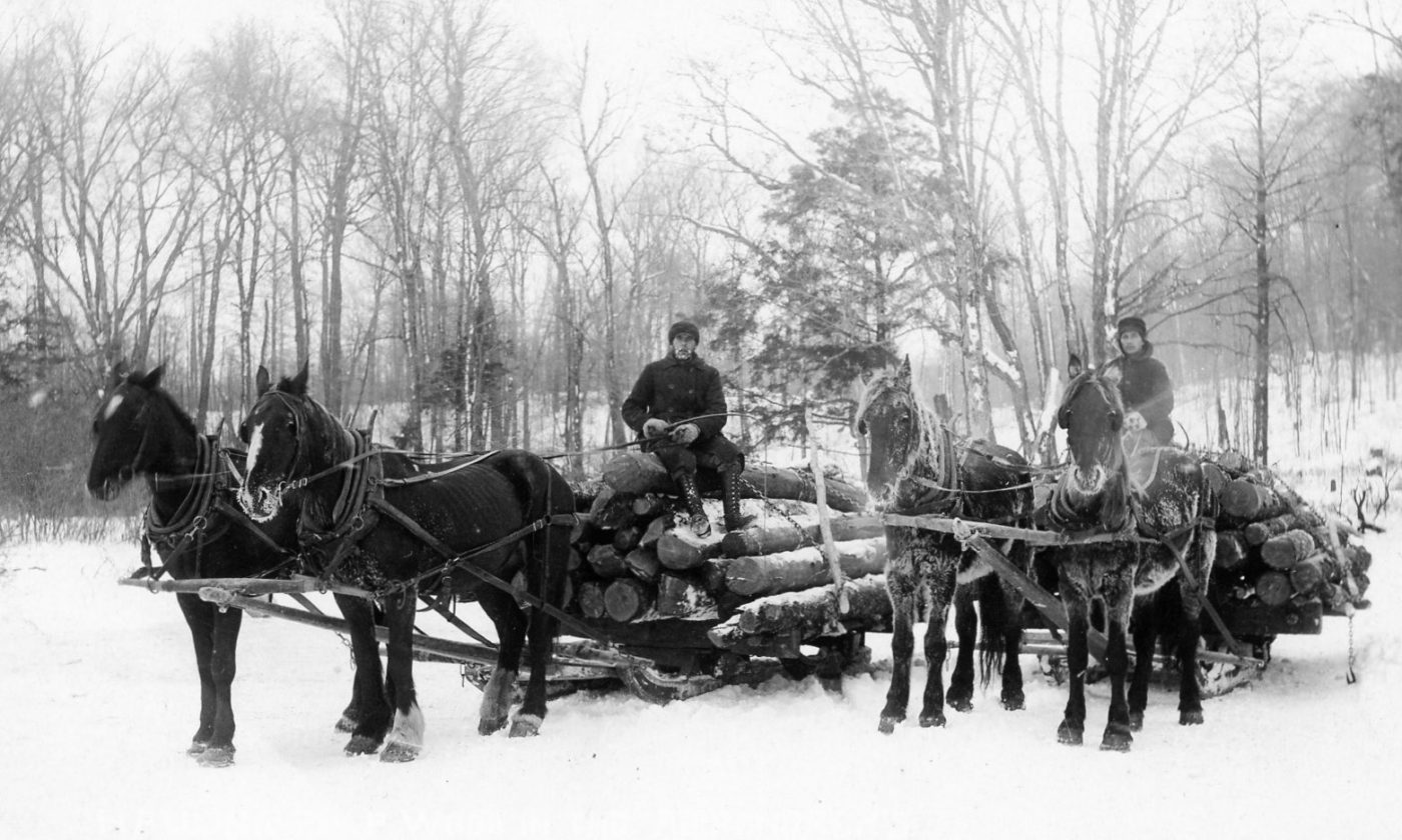 Two men driving log sleds in Hermon