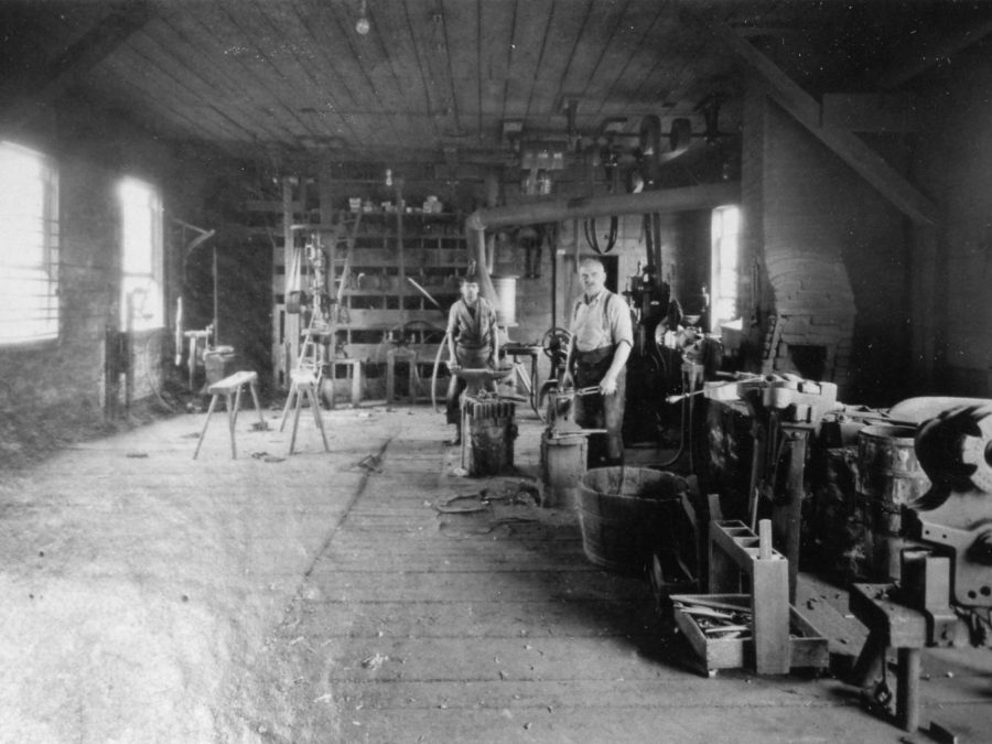Blacksmiths inside their blacksmith, wheelwright, and carriage shop in ...