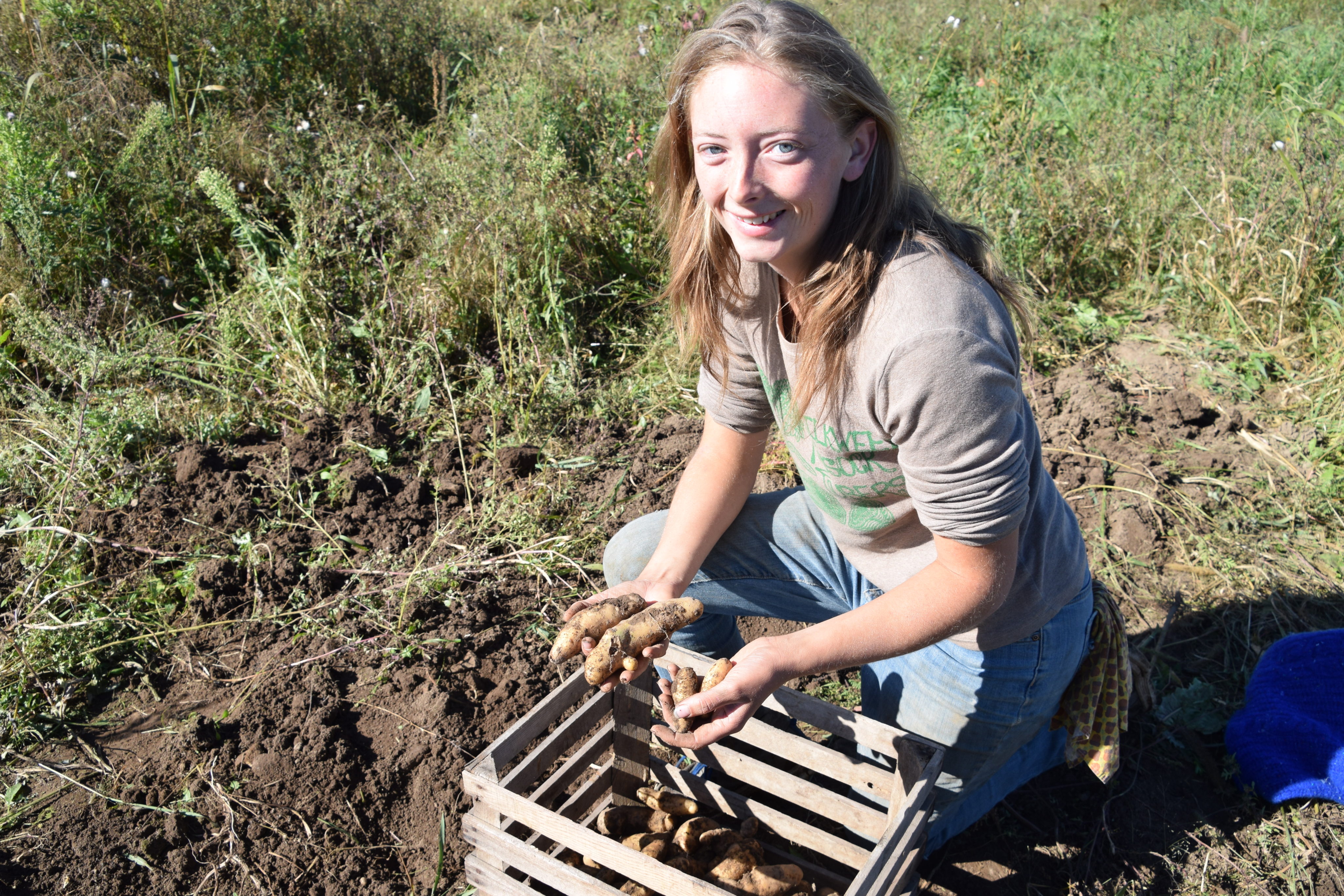 Cat Bennett posing with potatoes on her potato farm in De Peyster